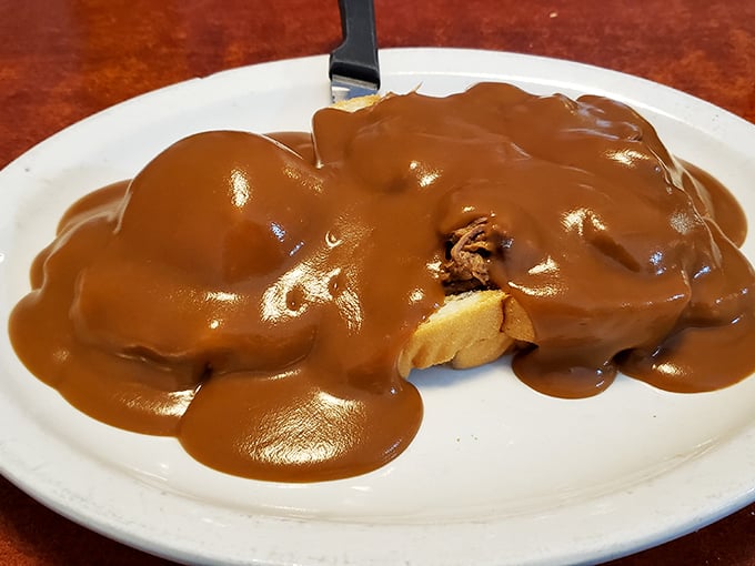 Hot roast beef drowning in rich brown gravy – the kind of open-faced sandwich that requires a fork, knife, and possibly a moment of silence.