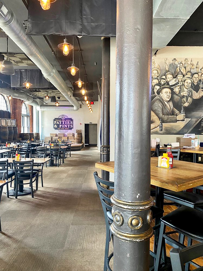 The spacious interior features industrial columns, vintage-inspired lighting, and a mural that tells stories of gatherings past – a modern speakeasy for food enthusiasts.