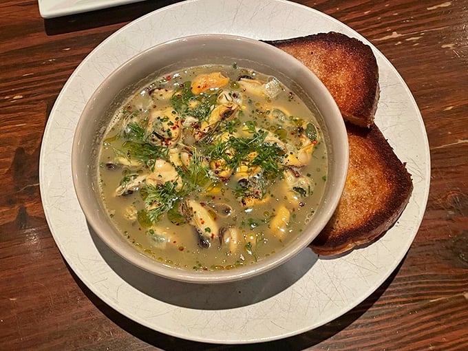 These mussels aren't just swimming in broth—they're doing the backstroke through a sea of herbs and butter that deserves its own Olympic medal.