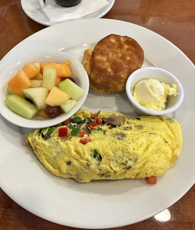 This isn't just an omelet – it's a morning masterpiece filled with fresh vegetables and served with fruit and a biscuit that could make a Southerner weep with joy.