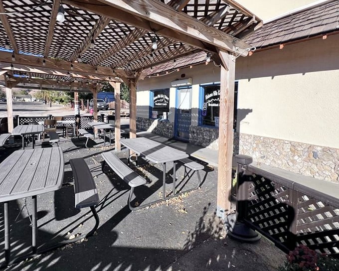 The outdoor seating area—where mountain air makes everything taste better. Simple picnic tables under dappled shade create breakfast nirvana.
