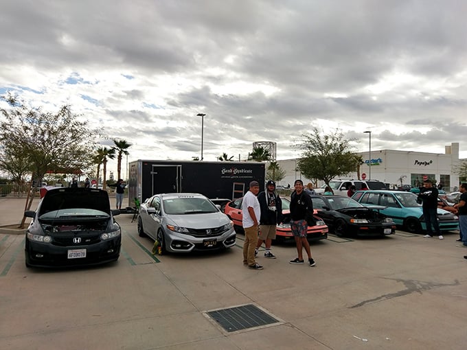 The parking lot: where car enthusiasts gather to admire engines while their passengers hunt for deals inside—a symbiotic relationship as old as retail itself.