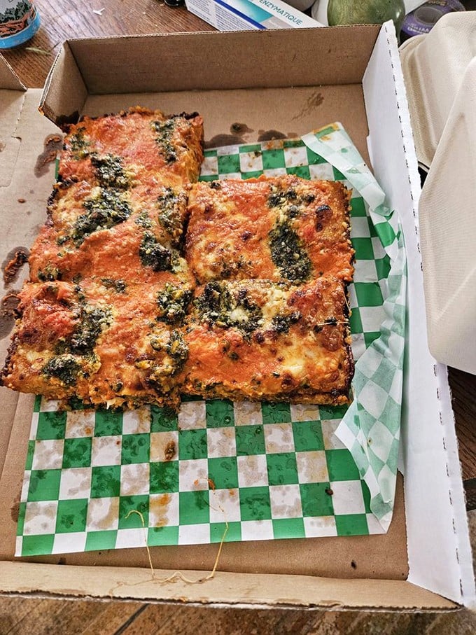 Red sauce and pesto join forces on this rectangular masterpiece—proof that world peace might be possible if we all just shared more pizza.