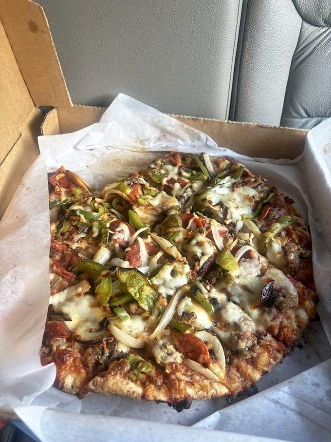 Pizza perfection in a box—where green peppers and onions dance across a landscape of melted cheese, proving that simple ingredients handled with care create magic.
