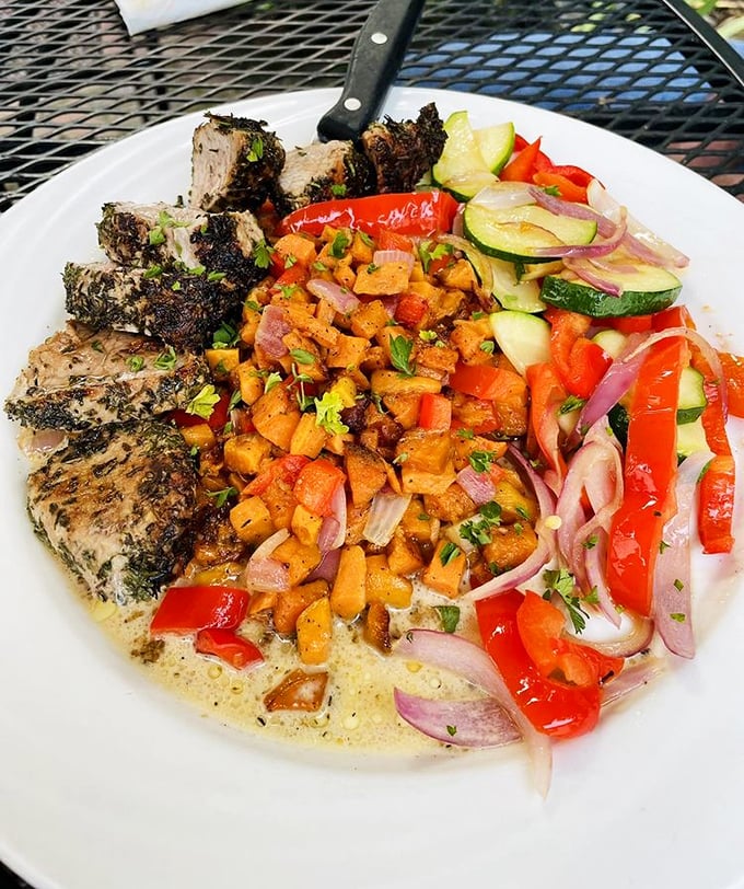 Herb-crusted pork tenderloin surrounded by a colorful medley of vegetables—proof that eating your veggies can be a revelation.