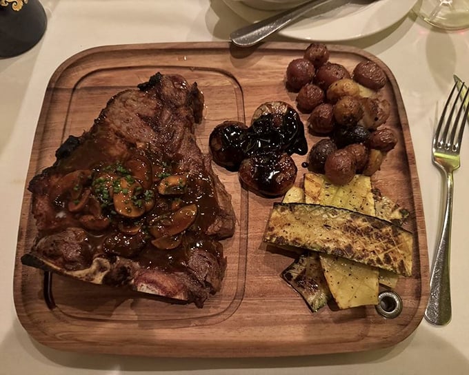 A steak served on wood with mushrooms and vegetables—because sometimes your meat deserves its own stage and supporting cast.