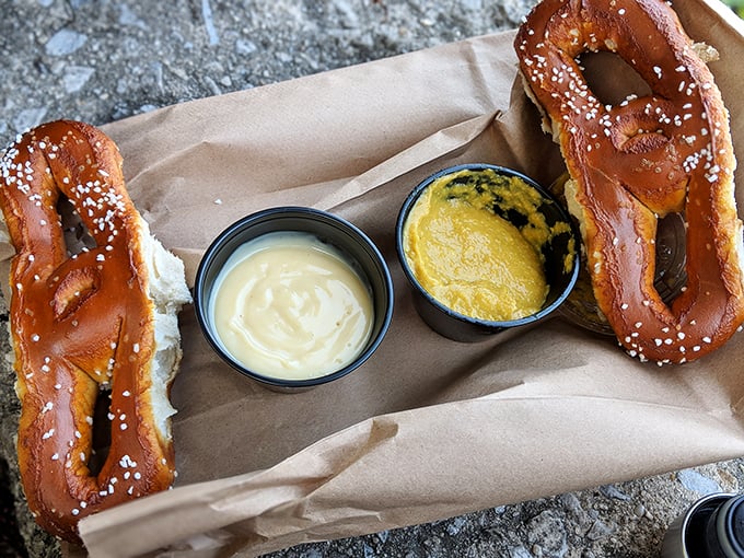 Two pretzels and dipping sauces on brown paper—street food elevated to an art form without losing its unpretentious soul. 