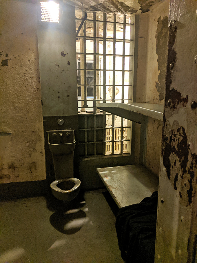 Five-star discomfort: metal bed, institutional toilet, and bars with a view. The cell's stark reality hits harder than any crime deterrent public service announcement.