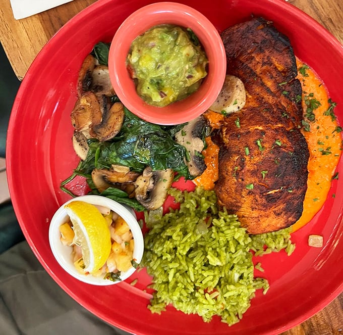 A plate so colorful it could double as modern art—blackened salmon resting on a bed of vibrant green rice with mushrooms playing supporting roles.