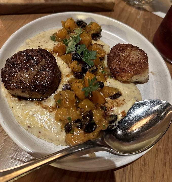 These scallops aren't just seared – they're transformed into golden medallions atop a creamy canvas of pure comfort.