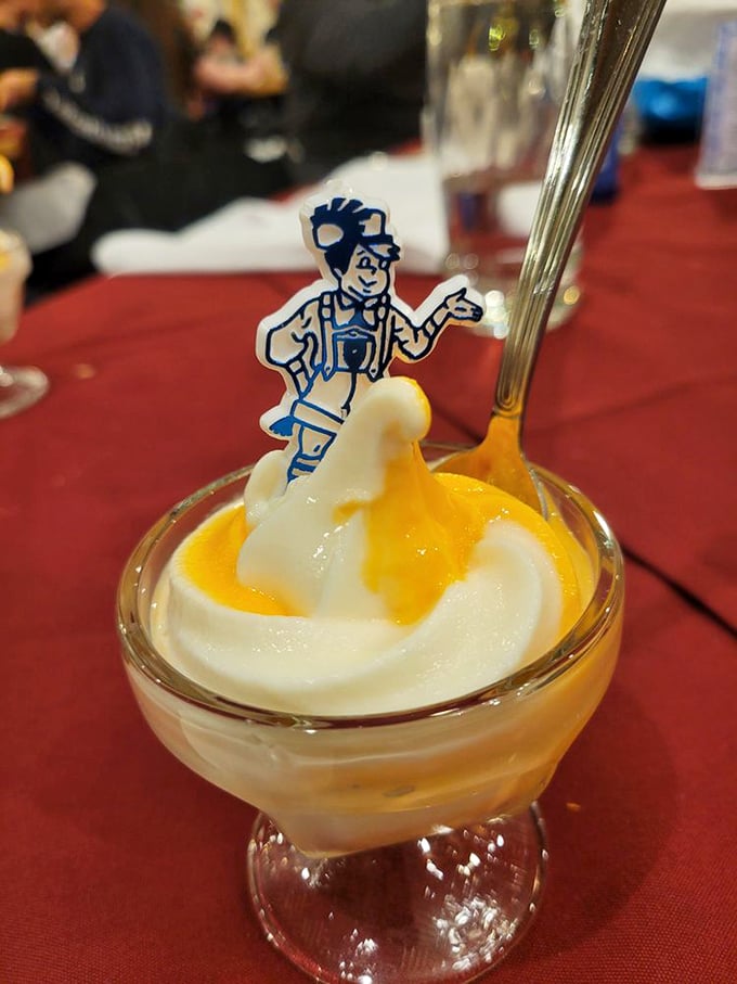 This isn't just dessert—it's a diplomatic summit between ice cream and fruit, with a little Bavarian mascot mediating the delicious negotiations.