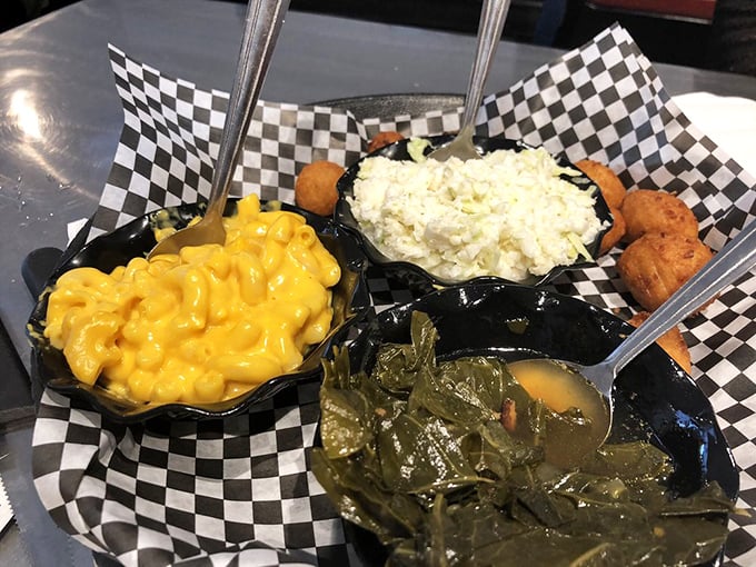 The holy trinity of Southern sides served in checkered baskets. Mac and cheese, potato salad, and collard greens – a supporting cast that steals the show.