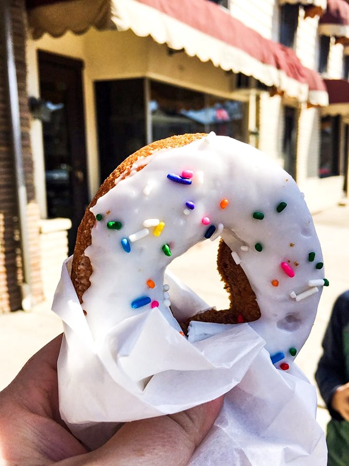 The white-glazed donut with sprinkles—proof that sometimes the classics endure for a reason. That paper wrapper is about to become very, very empty.