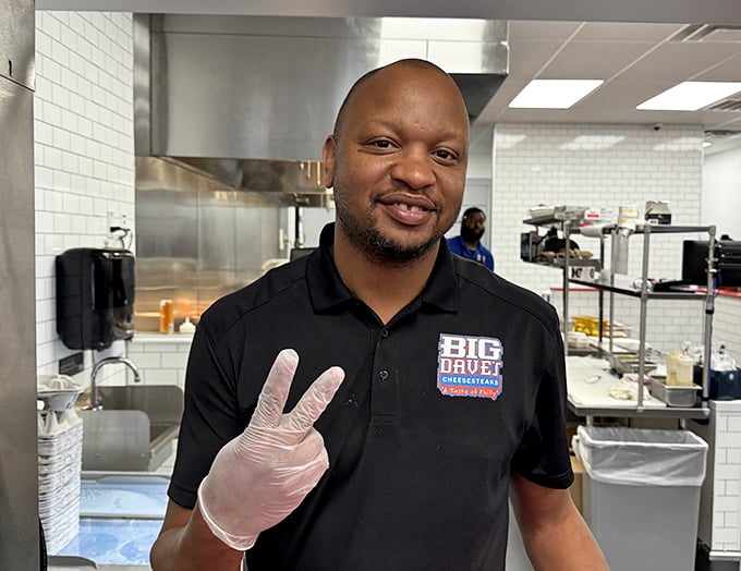 Behind every great cheesesteak is a team that understands the sacred bond between bread, meat, and cheese. The peace sign says it all—sandwich harmony achieved.