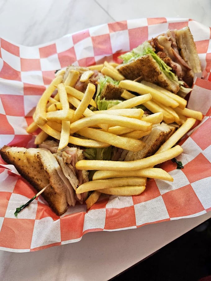 This club sandwich with golden fries isn't just lunch—it's edible architecture, carefully constructed layers of comfort that make you forget salads were ever invented.