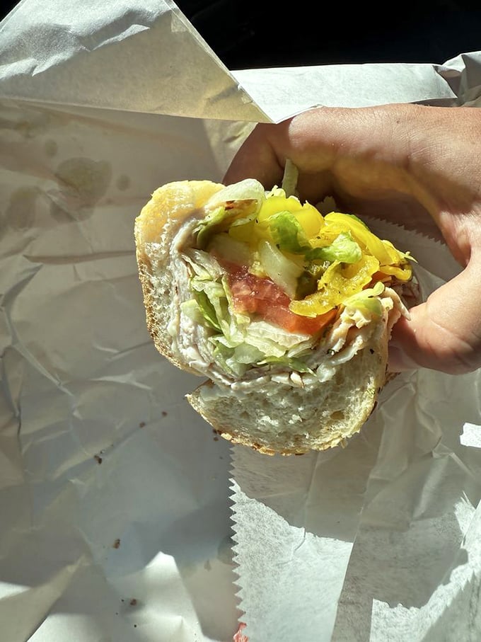 A half-eaten hoagie reveals its secrets—layers of meat, cheese, and veggies in perfect proportion. Someone couldn't wait to finish before taking a photo.