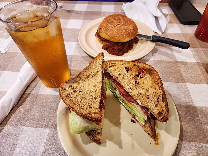 A sandwich cut on the diagonal—as civilization demands—revealing layers of BLT perfection. Sweet tea standing by for the necessary refreshment.