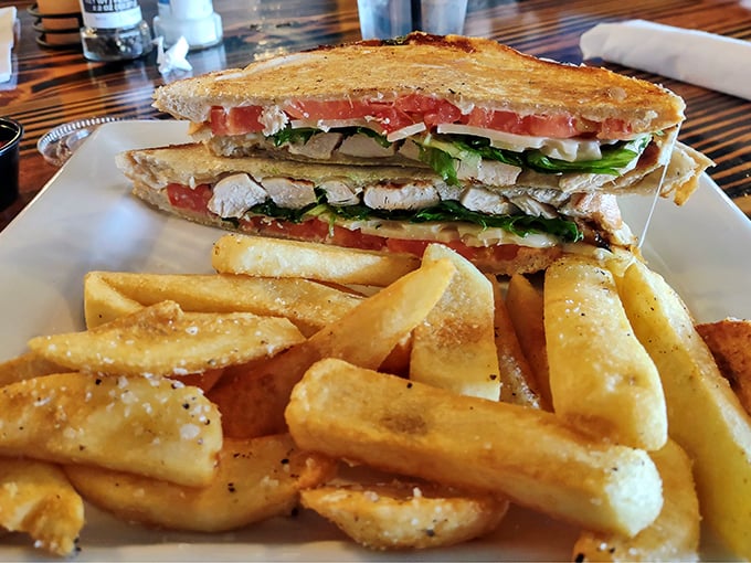This sandwich means business—layers of chicken, fresh vegetables, and what looks like melty cheese, escorted by golden fries that demand equal attention.