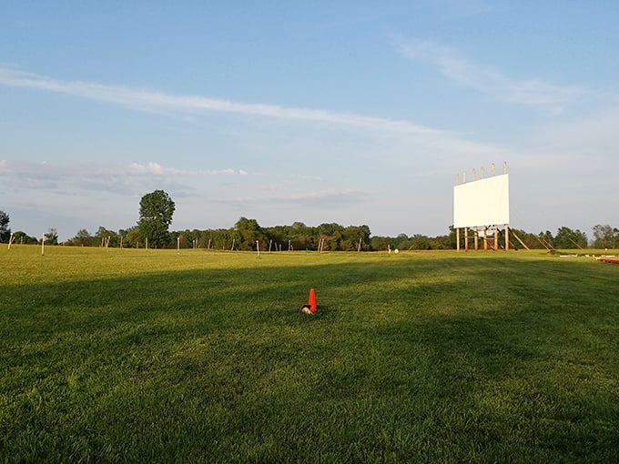 The wide-open field waits patiently for the evening crowd, a blank canvas of possibility marked only by a lonely orange cone.