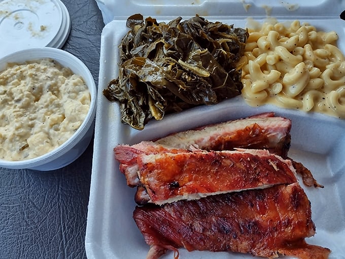 A tray of smoky goodness featuring ribs, collard greens, and mac and cheese—the barbecue trifecta that makes resistance futile.