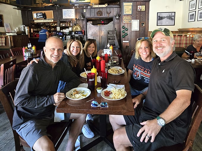 Happy diners sharing stories and meals – the universal language of good food bringing people together around a wooden table.
