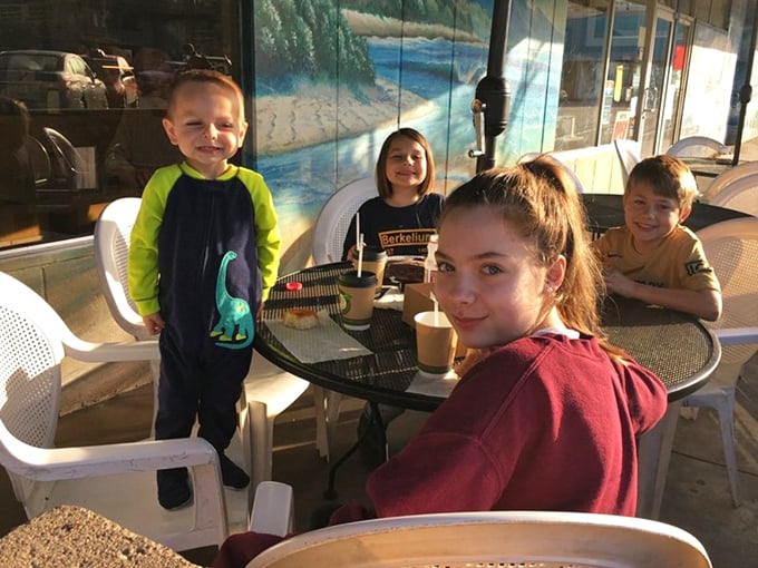 Kids plus sugar equals pure joy—this outdoor table captures the universal truth that donuts are happiness delivery devices.