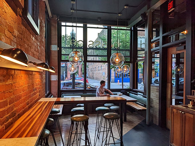 Corner seating bathed in natural light with pendant globes hanging like modern art—the perfect perch for people-watching between bites of brilliance.