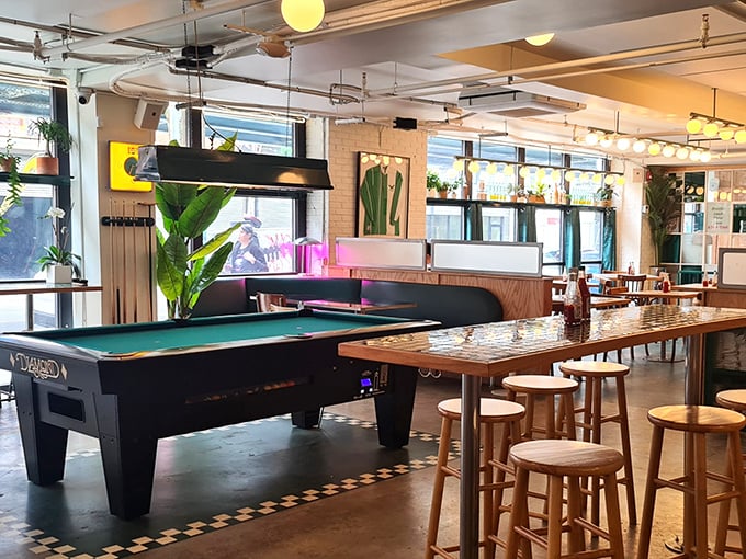 Not just food but fun—a pool table stands ready for between-bite entertainment in this plant-filled, light-drenched corner.