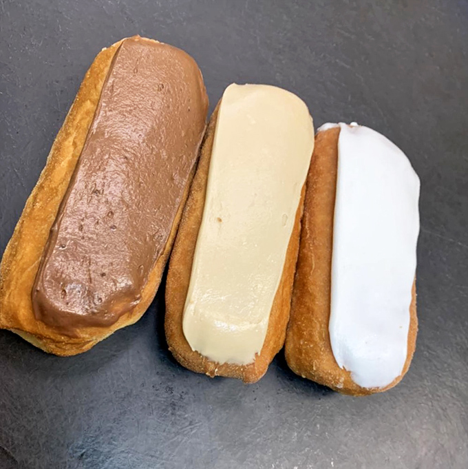The holy trinity of éclairs—chocolate, vanilla, and white—each one a perfect vessel of creamy filling encased in tender pastry that shatters just right.