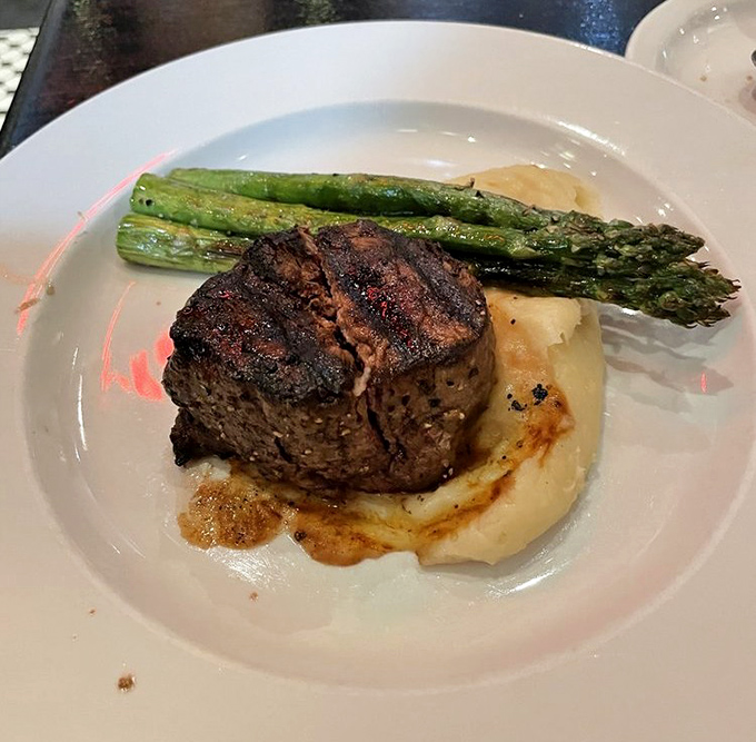 This filet mignon with asparagus spears isn't just dinner – it's proof that steakhouse classics can swim comfortably in seafood waters. 