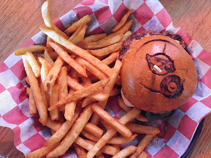 A burger branded with the restaurant's logo, because when food tastes this good, it deserves a signature. Fries looking equally spectacular.