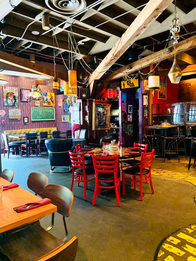 Red chairs pop against artistic chaos—dining here feels like eating inside a painter's imagination after they've had their morning coffee.