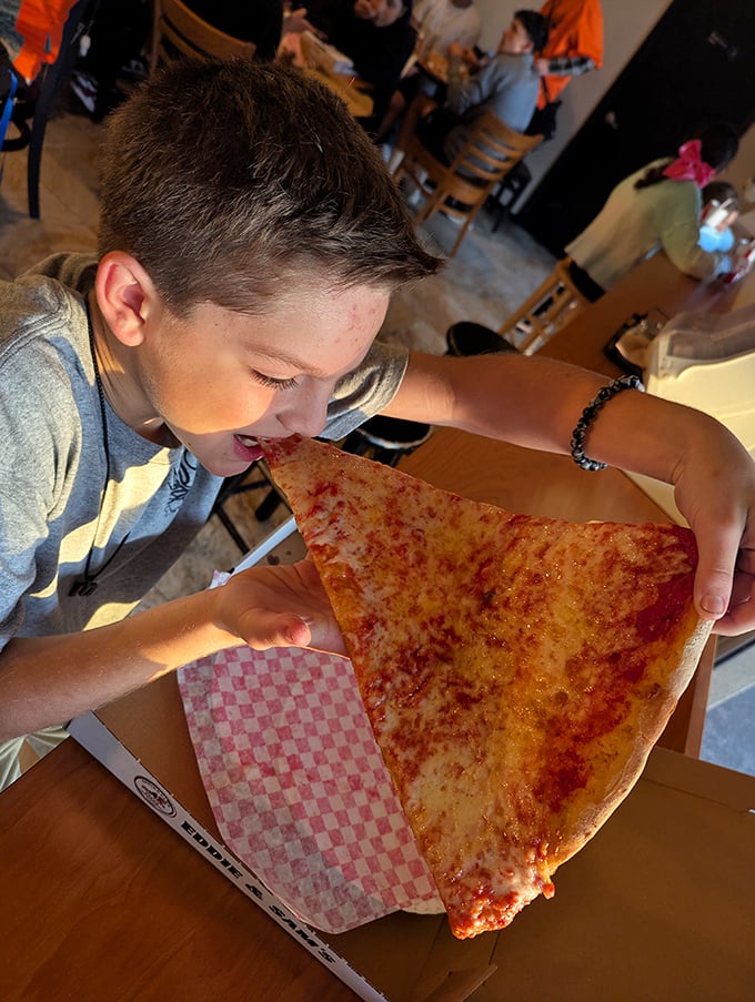 The universal language of pizza joy – when that first bite creates a moment of pure childhood bliss regardless of your actual age.