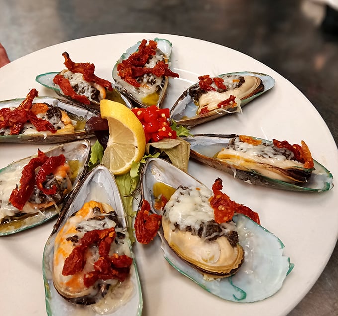These mussels aren't just seafood—they're little boats delivering sun-dried tomatoes and cheese directly to your happiness receptors. The lemon stands by, ready for duty.
