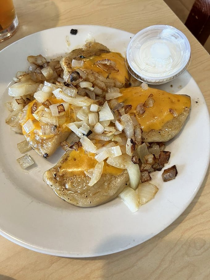 Pierogies topped with melted cheese and caramelized onions—proof that sometimes the simplest combinations create the most profound comfort.
