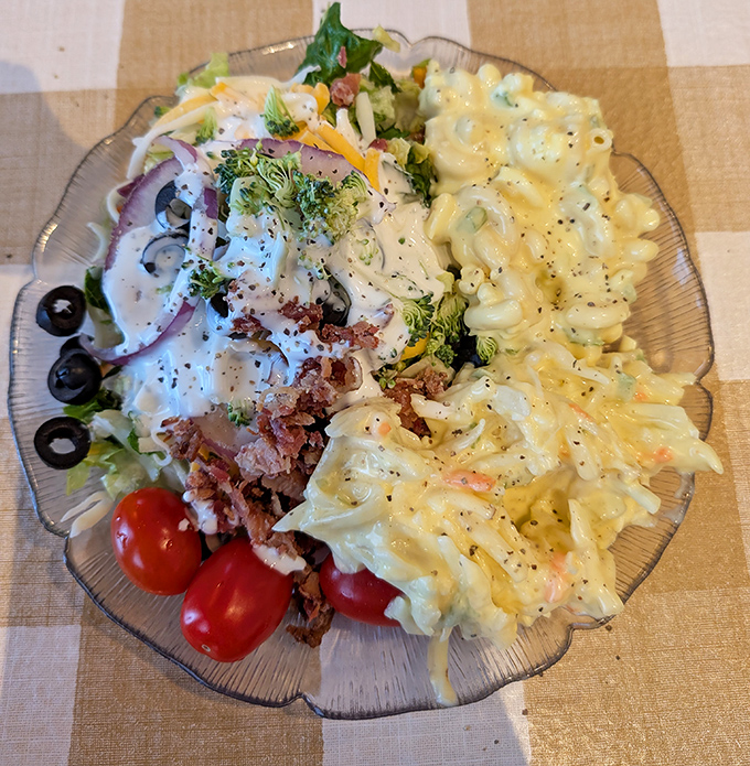 A glass plate divided like the perfect marriage—garden-fresh salad on one side, creamy macaroni on the other, proving opposites really do attract.
