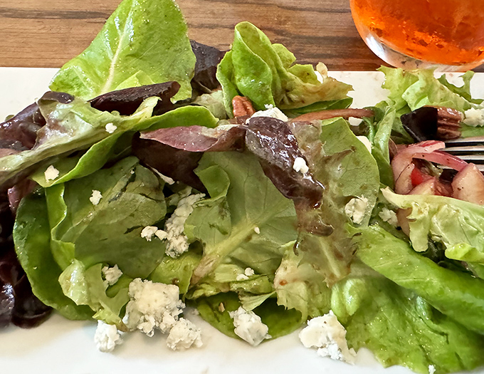 Even the salads deserve attention – fresh greens, crumbled cheese, and a light dressing create the perfect opening act before the main pizza event.