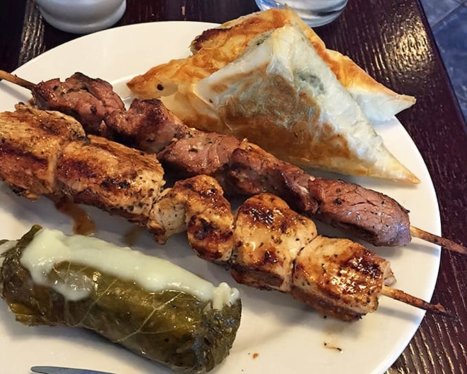 A plate that solves indecision—skewers of perfectly grilled meats, a dolmade standing at attention, and triangles of phyllo that shatter with each bite.