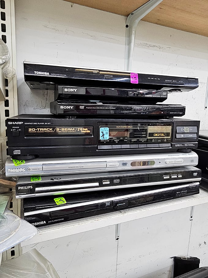 The electronics graveyard houses DVD players and stereo components from an era when instruction manuals were thicker than smartphones.