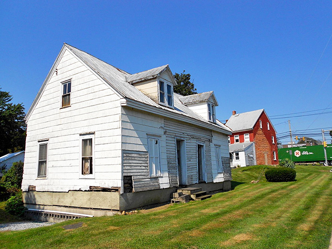 This weathered white New Holland homestead tells tales of yesteryear, while its red brick neighbor and green train car listen intently.