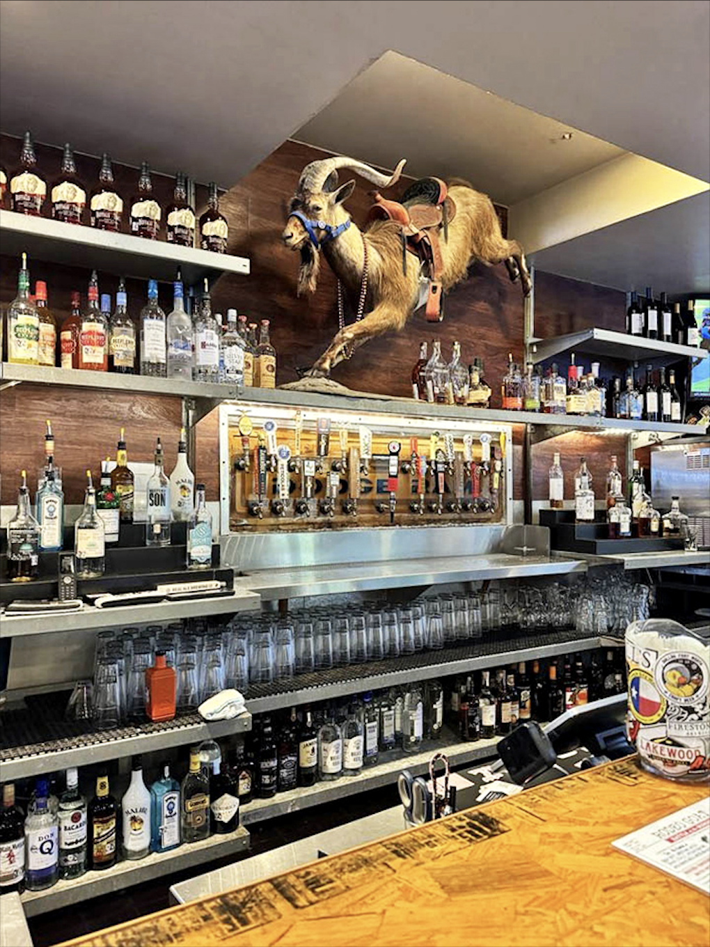 The bar area showcases an impressive selection of craft beers and spirits beneath that iconic rodeo artwork.
