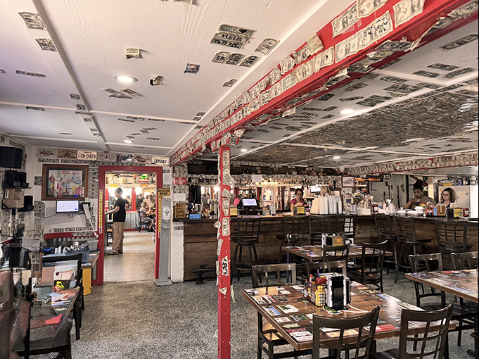 Dollar bills papering every surface tell stories of visitors past—a currency collage that's part decor, part guest book, all character.