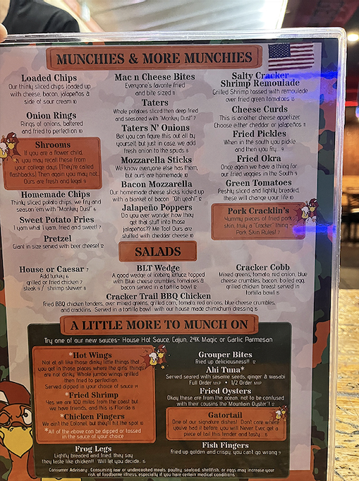 The menu reads like a love letter to comfort food – from loaded chips to frog legs that "taste like chicken," each description carries a dash of personality.