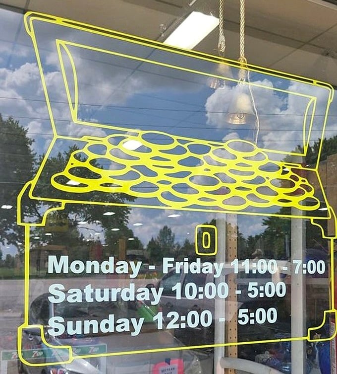 The store hours sign, framed in neon yellow, beckons bargain hunters like a lighthouse guiding ships to the shores of secondhand treasures.