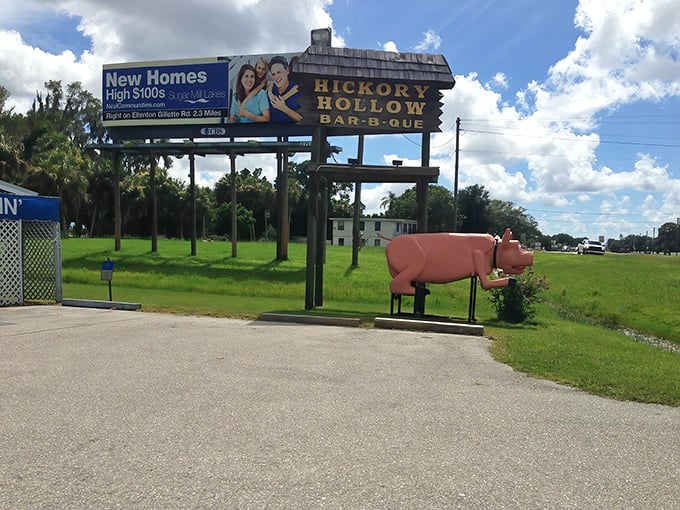 The iconic Hickory Hollow sign stands tall with its pink pig guardian below—a roadside beacon promising smoky delights and seafood surprises.
