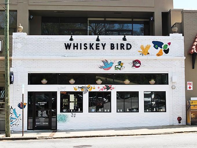The colorful bird murals adorning Whiskey Bird's white brick façade aren't just decoration—they're a promise of the vibrant flavors waiting inside this Atlanta gem.