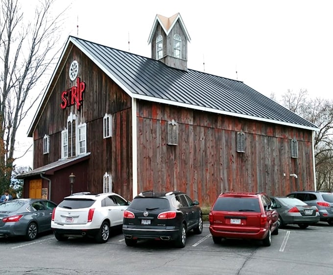 The weathered barn exterior of Strip Steakhouse stands as a delicious contradiction—rustic farmhouse on the outside, culinary paradise within.