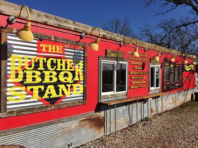 The bright red exterior of The Butcher BBQ Stand isn't just eye-catching—it's a smoke signal to barbecue pilgrims that they've reached the promised land.