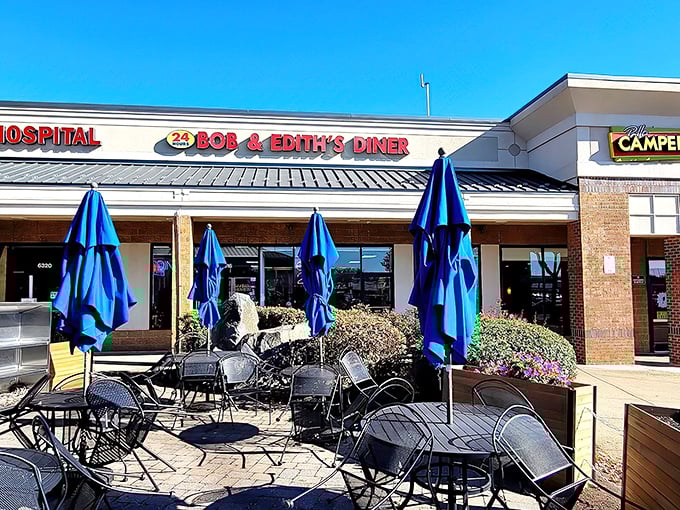 The classic red signage of Bob & Edith’s Diner beckons like a lighthouse for the hungry, its bright blue umbrellas adding a cheerful touch to a 24-hour haven where comfort and calories are always on the menu.