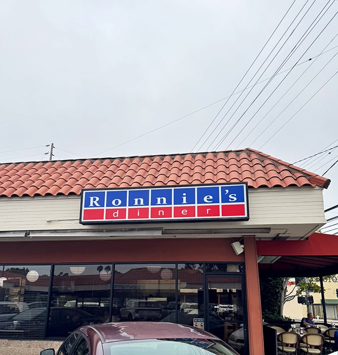 The iconic blue and red sign of Ronnie's Diner stands proudly against the California sky, promising breakfast salvation beneath that distinctive terra cotta roof.